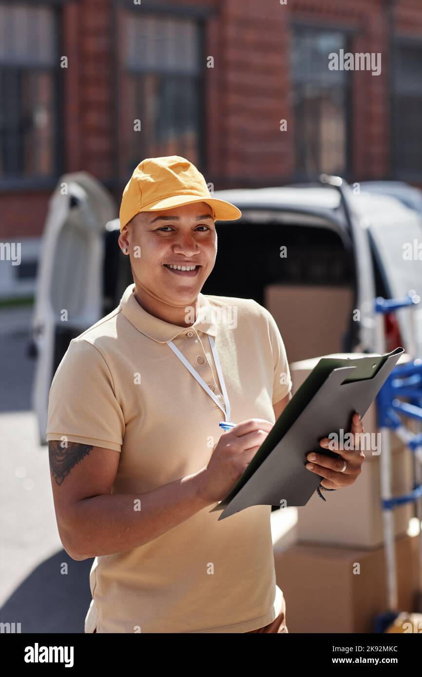 Vertical portrait of smiling delivery worker holding clipboard box ...