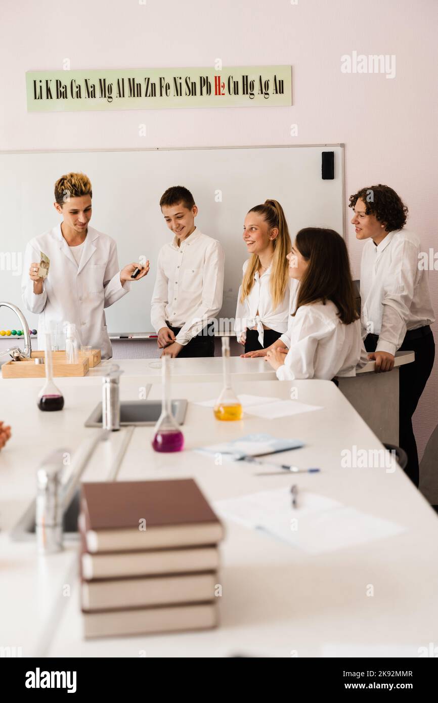 Discussion with a teacher at a chemistry lesson in a laboratory. Group ...