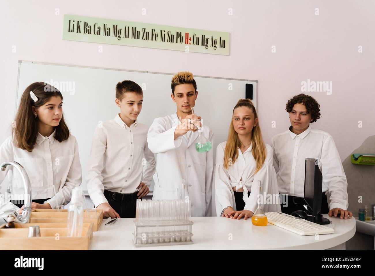 School chemistry teacher shows children flasks with liquids for ...