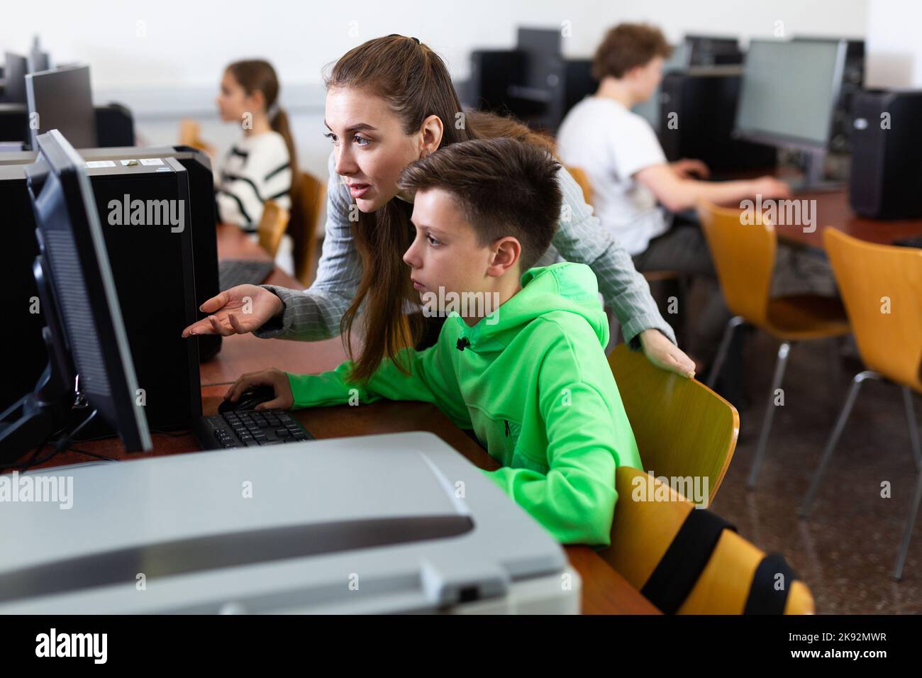 Teacher helping boy to solve computer problem Stock Photo - Alamy