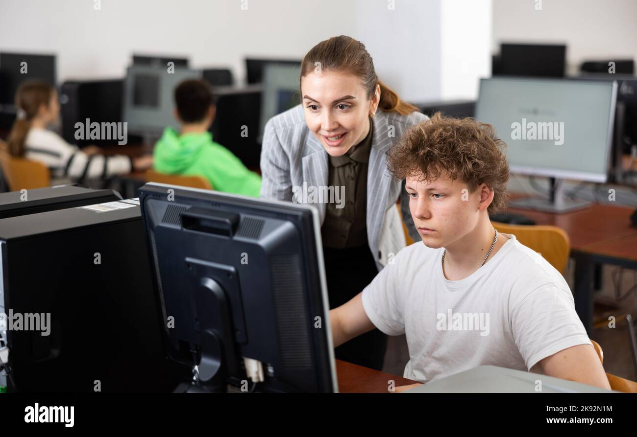 Teacher helping boy to solve computer problem Stock Photo - Alamy
