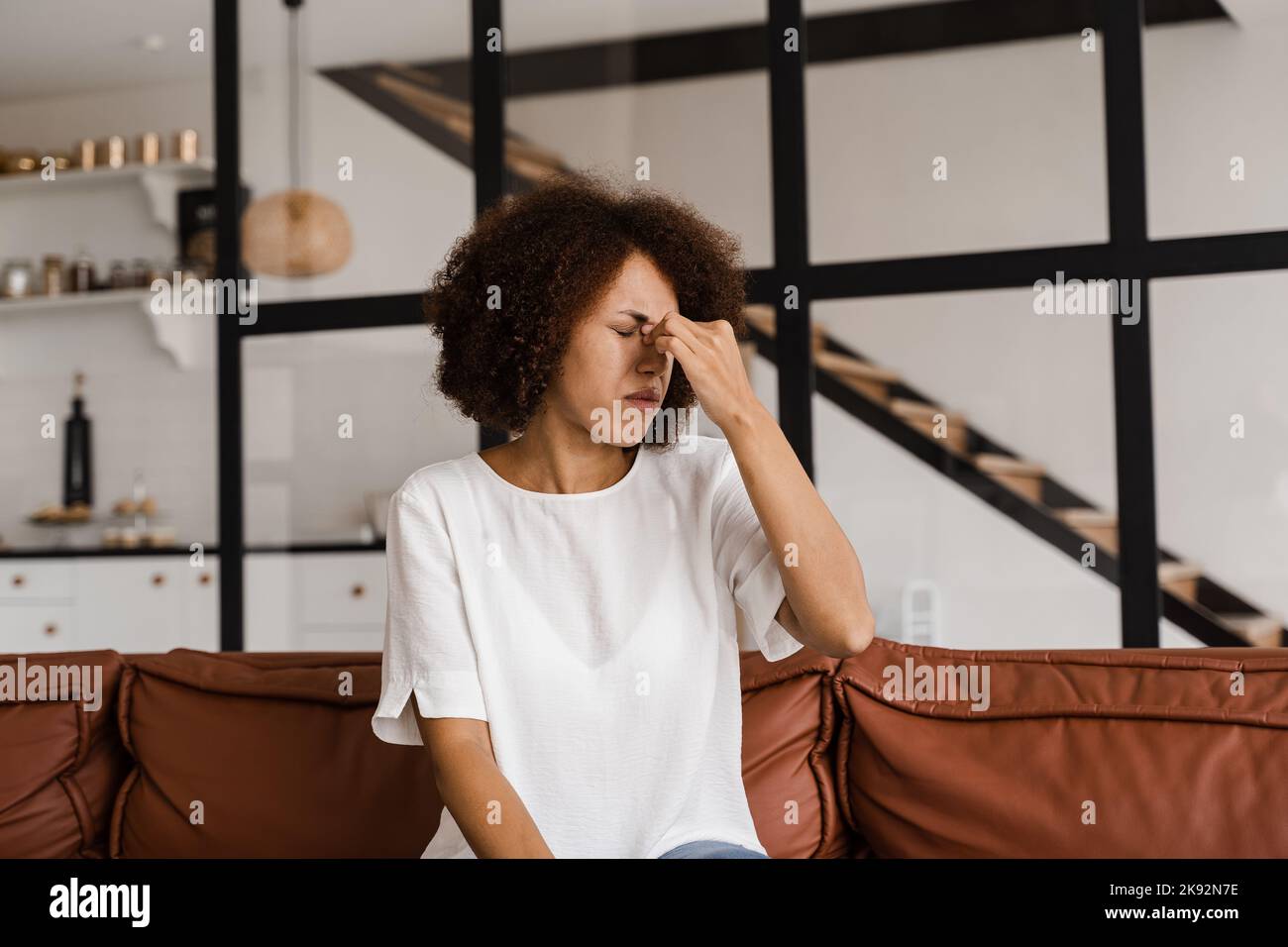 Sick African girl with sinusitis is holding her stuffy nose because she ...