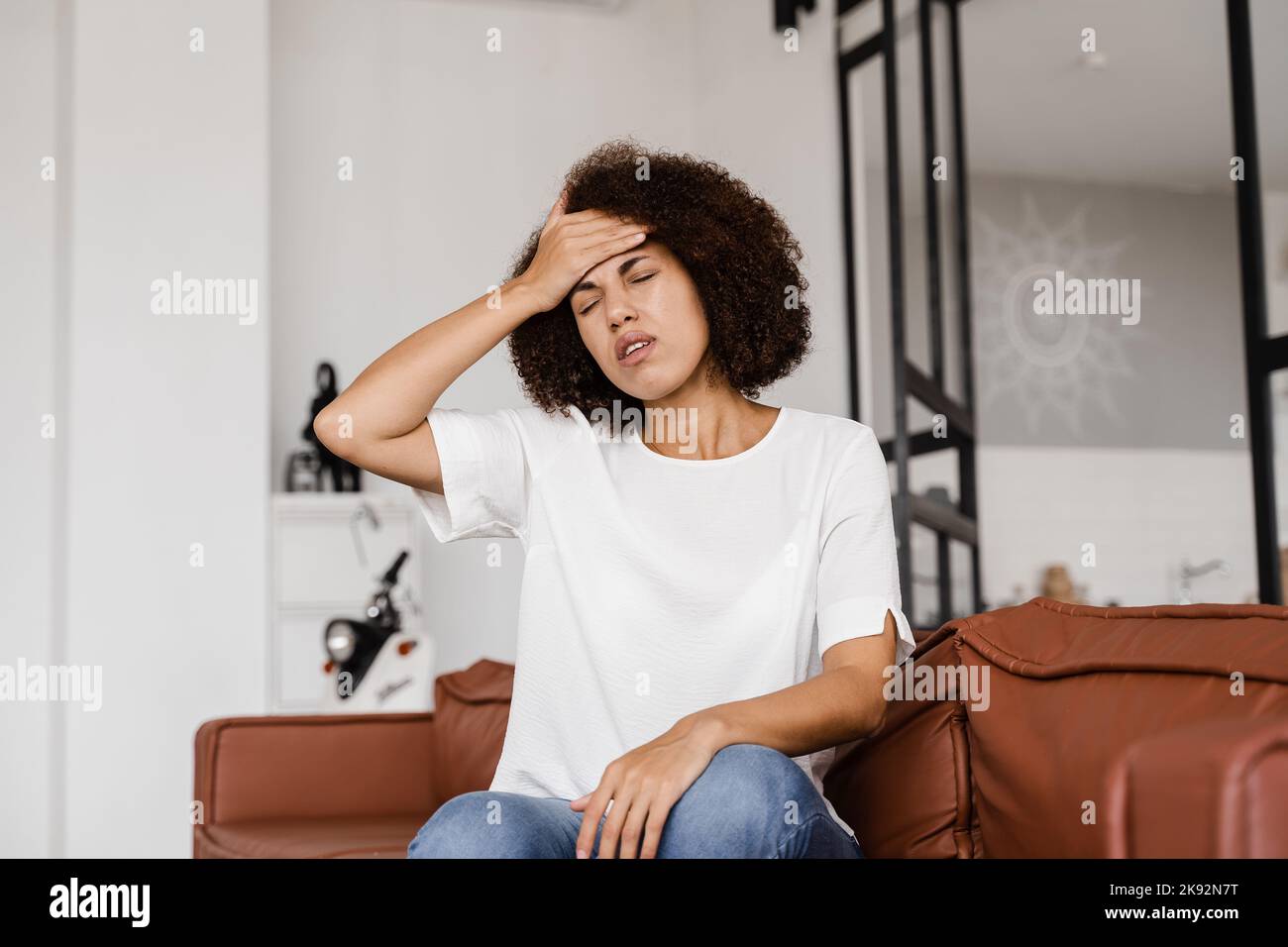 Sick African American woman has fever and touches her forehead with her ...