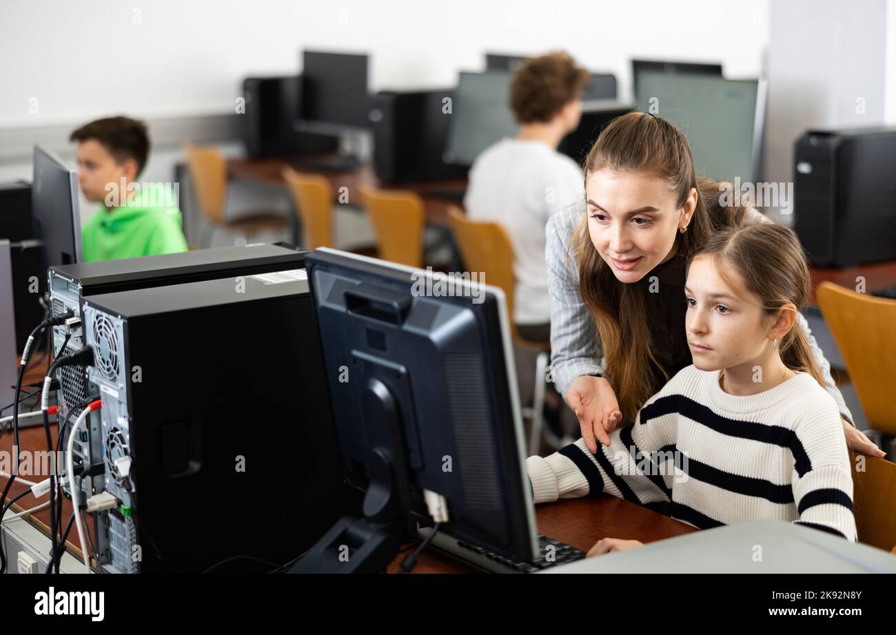 Female teacher helping teen schoolgirl studying in computer lab Stock ...