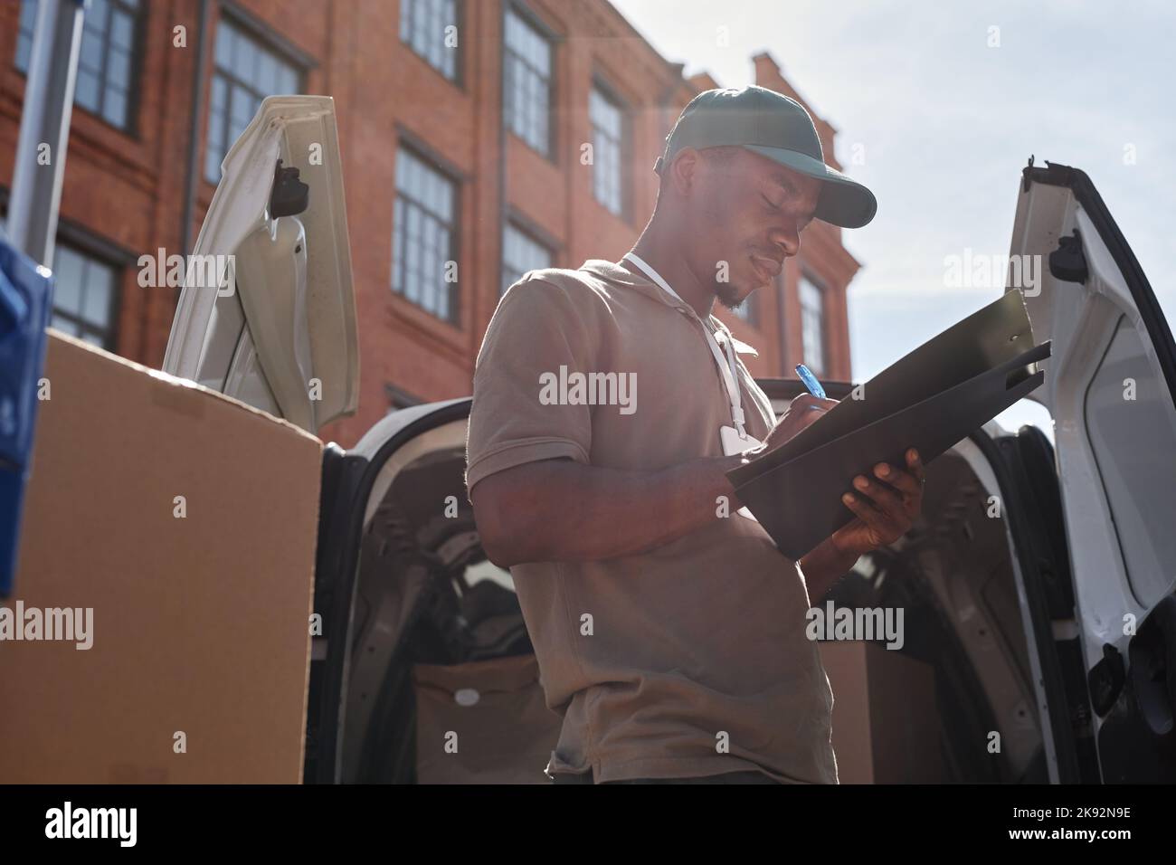 Side view portrait of black young man delivering packages in sunlight ...