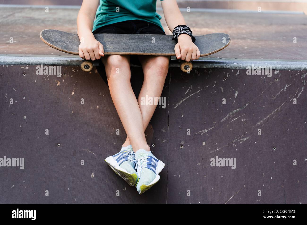 Child boy sitting with skate board close-up. Sports equipment for kids ...