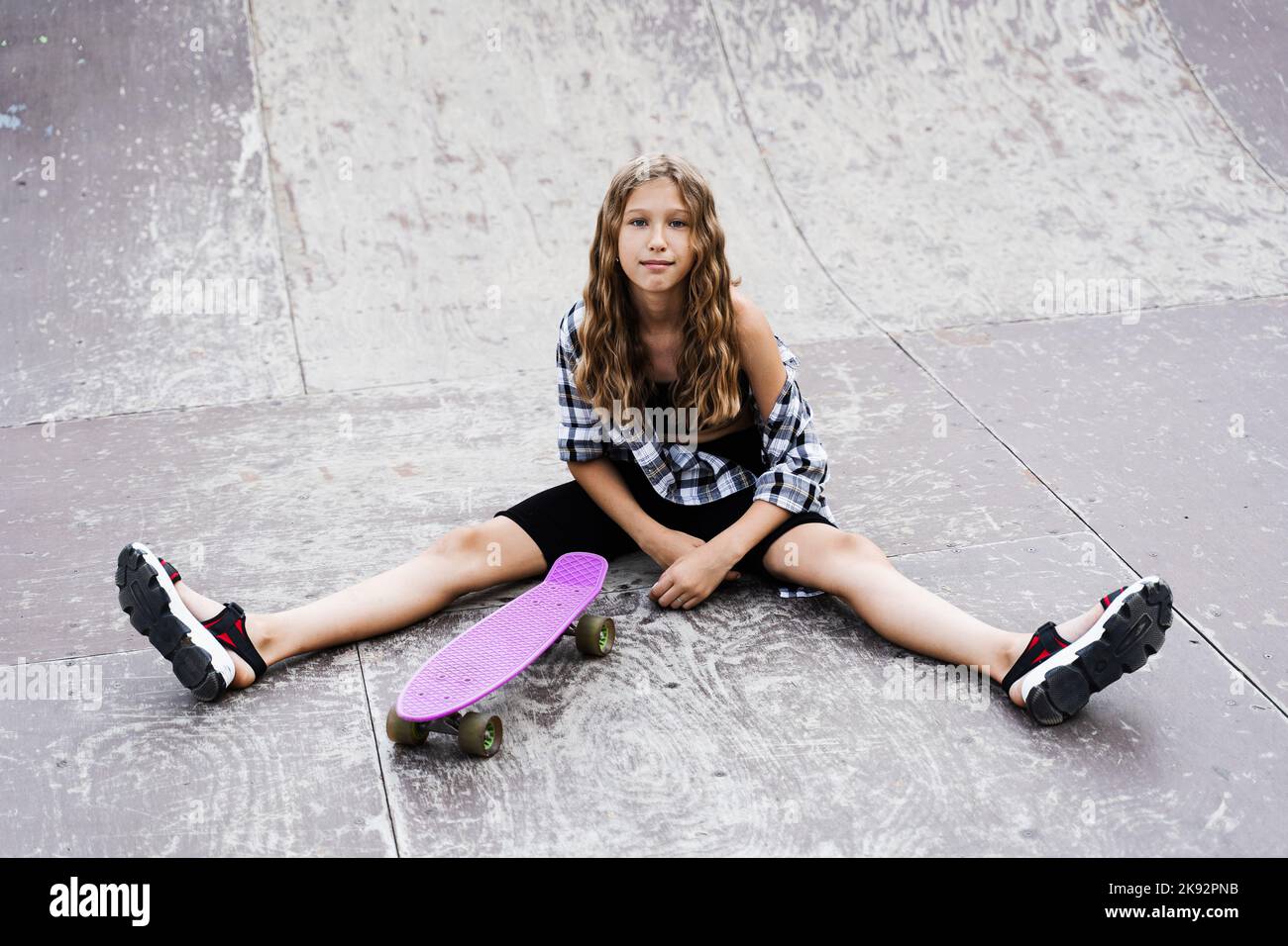 Attractive child with penny board sitting on sport ramp on skate ...
