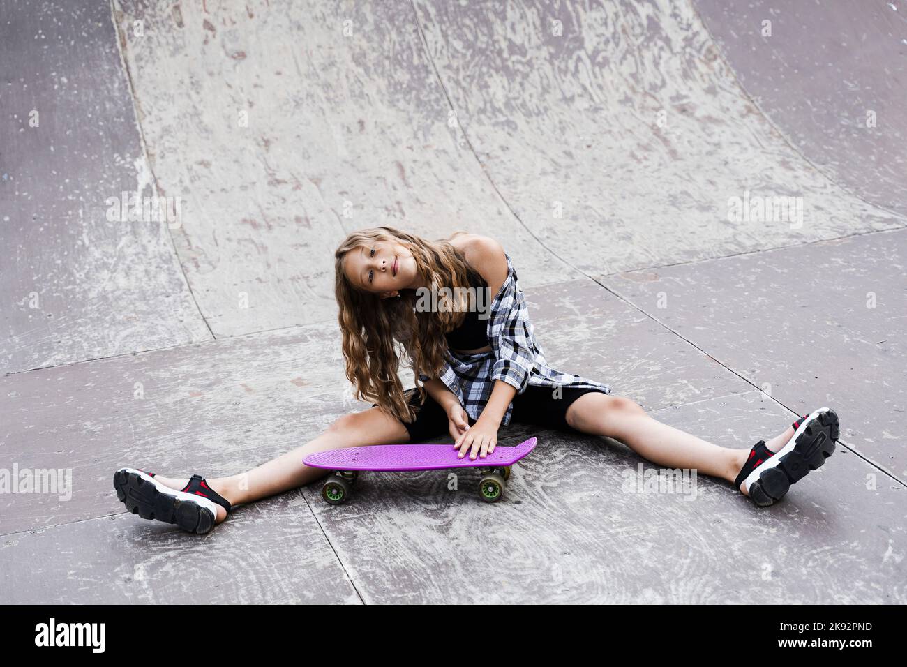 Attractive child with penny board sitting on sport ramp on skate ...