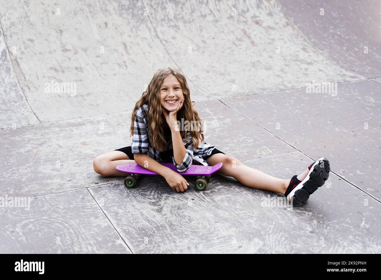 Attractive child with penny board sitting on sport ramp on skate ...