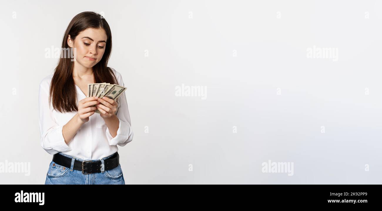 Sad woman counting money, lacking cash, standing gloomy over white ...