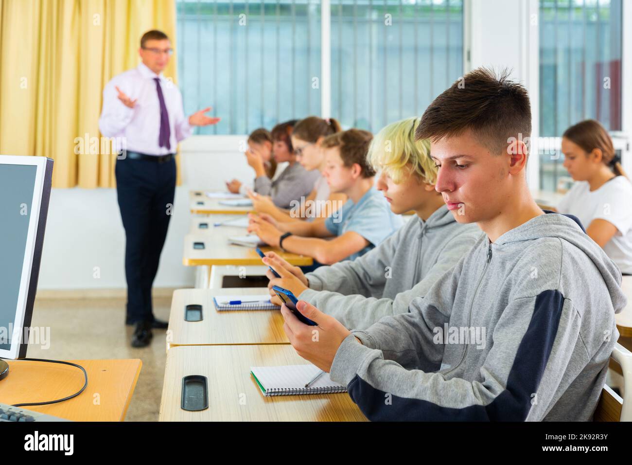 Teenage students using smartphones during lesson Stock Photo - Alamy