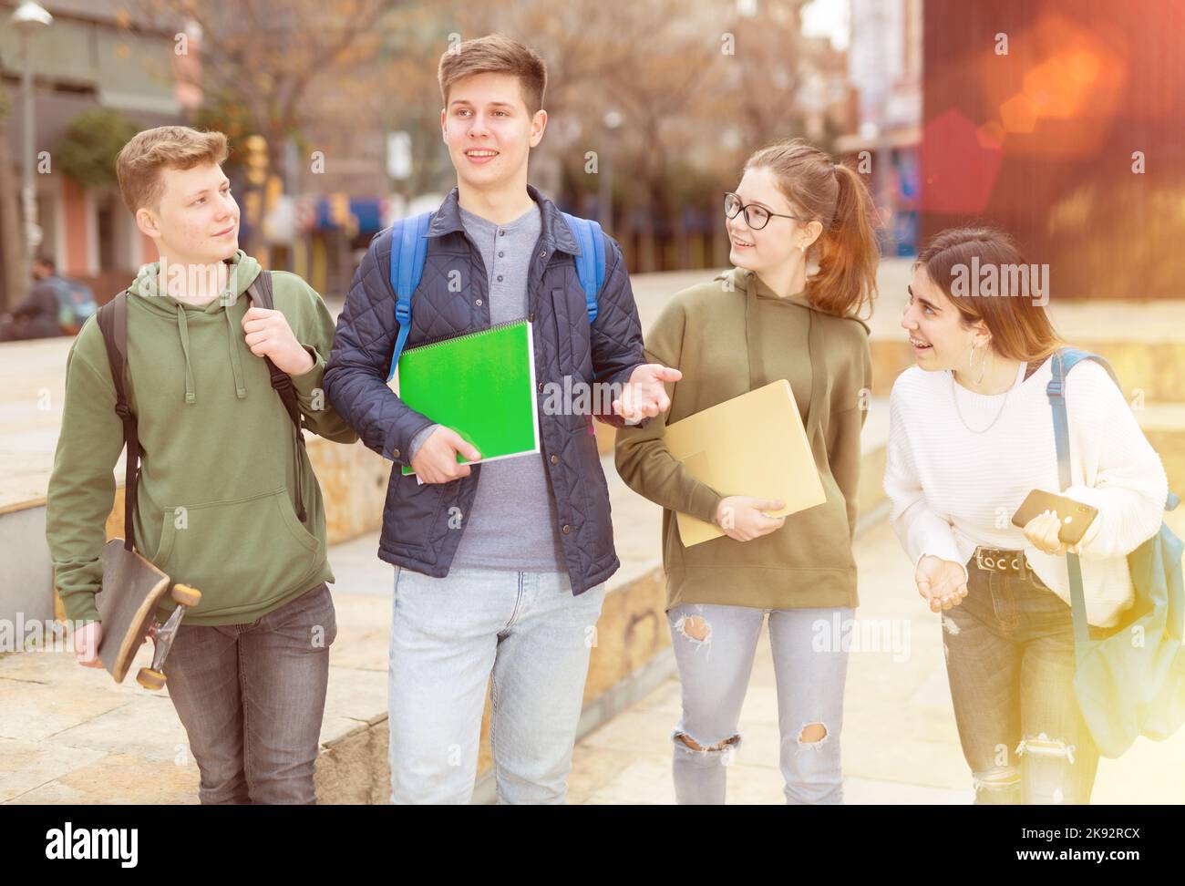 Four teenagers talking about play on walk in street Stock Photo - Alamy