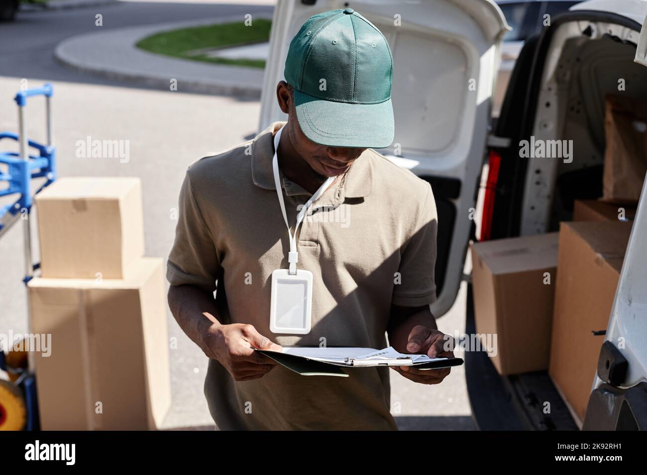 Portrait of young delivery man checking documents while unloading delivery van Stock Photo - Alamy
