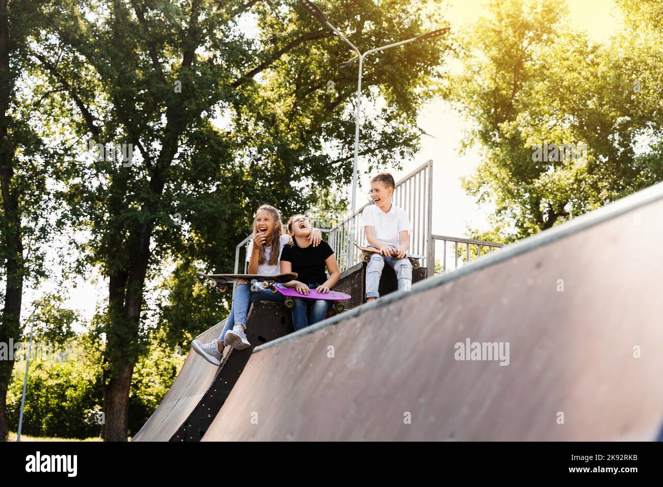 Sports kids with skateboard and penny boards are sitting and chatting ...
