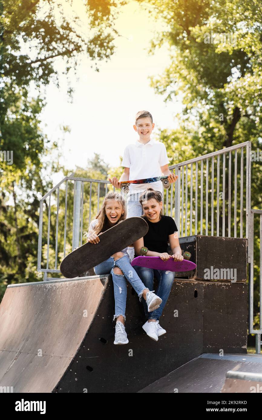 Sports kids with skateboard and penny boards are sitting and chatting ...