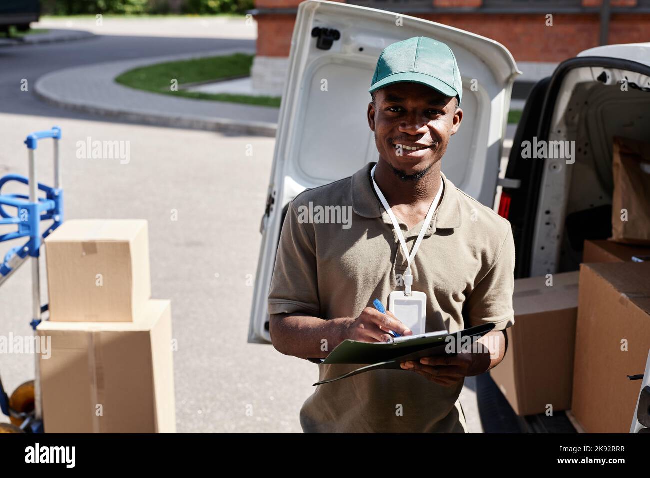 Waist up portrait of delivery man checking documents and looking at ...
