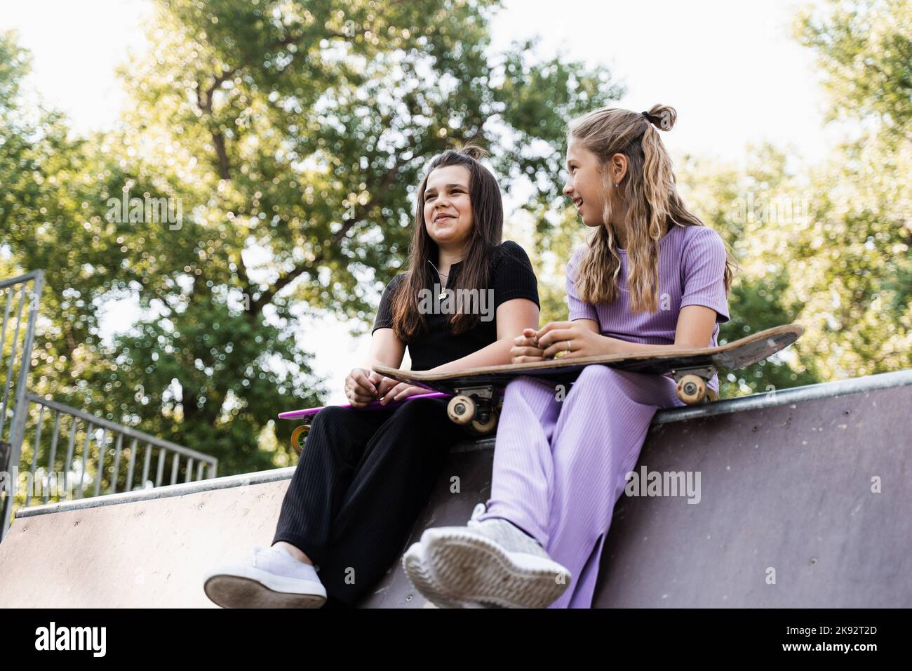 Sporty children girls with skateboard and penny boards are sitting and ...