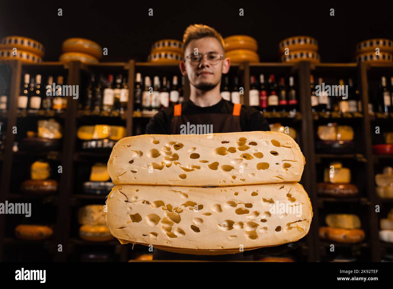 Cheese sommelier in food shop worker holding 2 big pieces of cheese ...