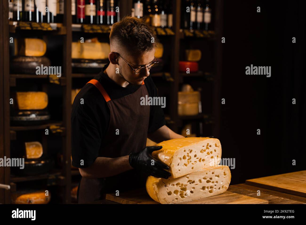 Cheese sommelier in food shop worker holding 2 big pieces of cheese ...
