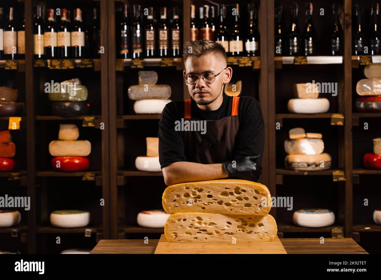 Professional cheese sommelier in food shop. Worker of cheese store with ...