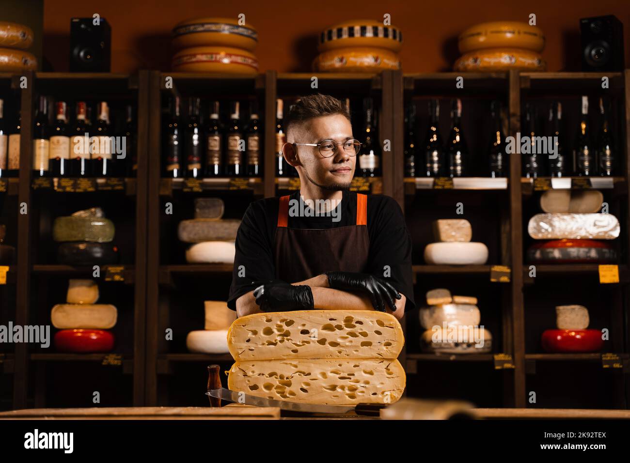 Professional cheese sommelier in food shop. Worker of cheese store with ...