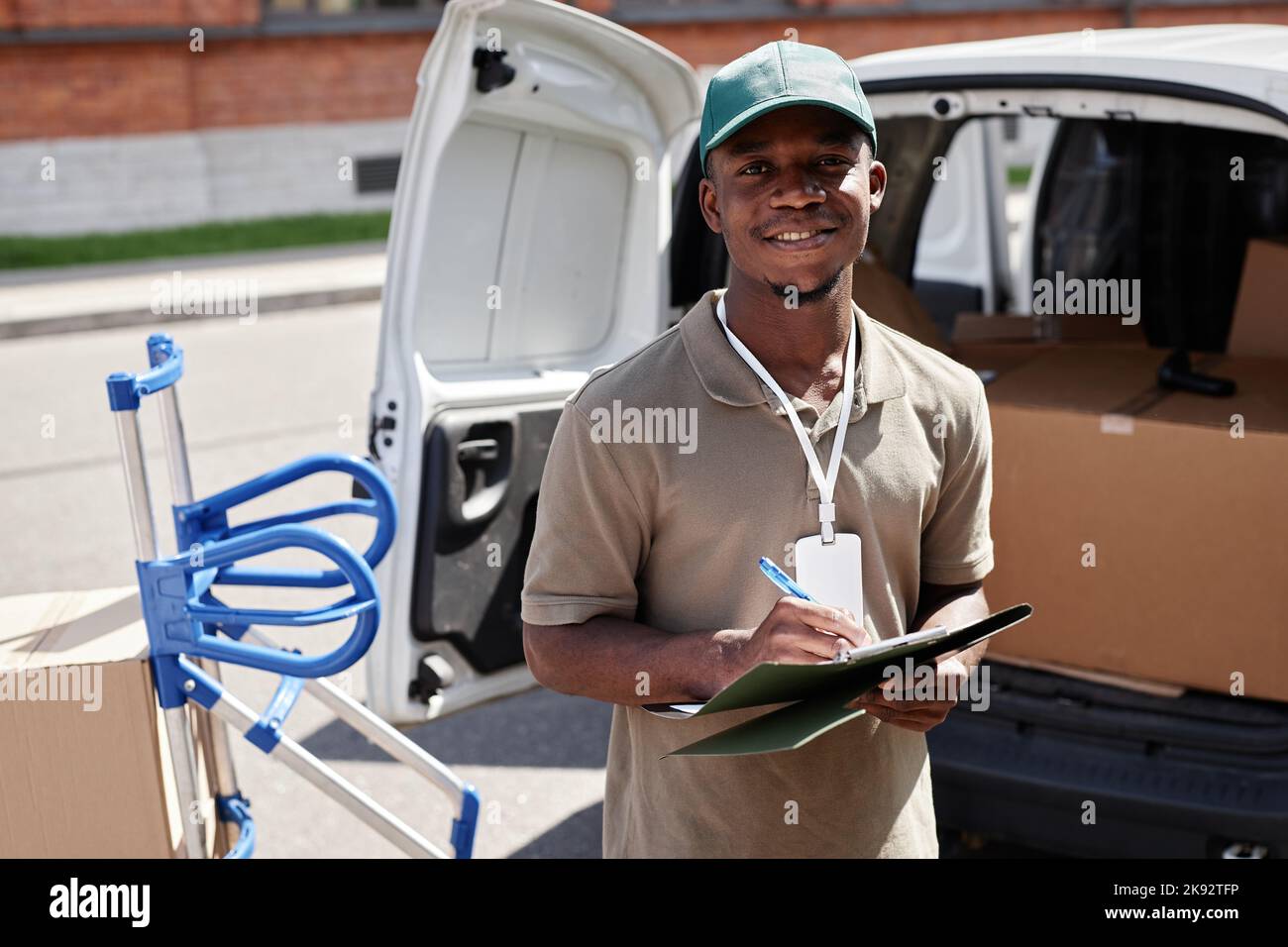 Waist up portrait of black young man unloading van with packages and ...