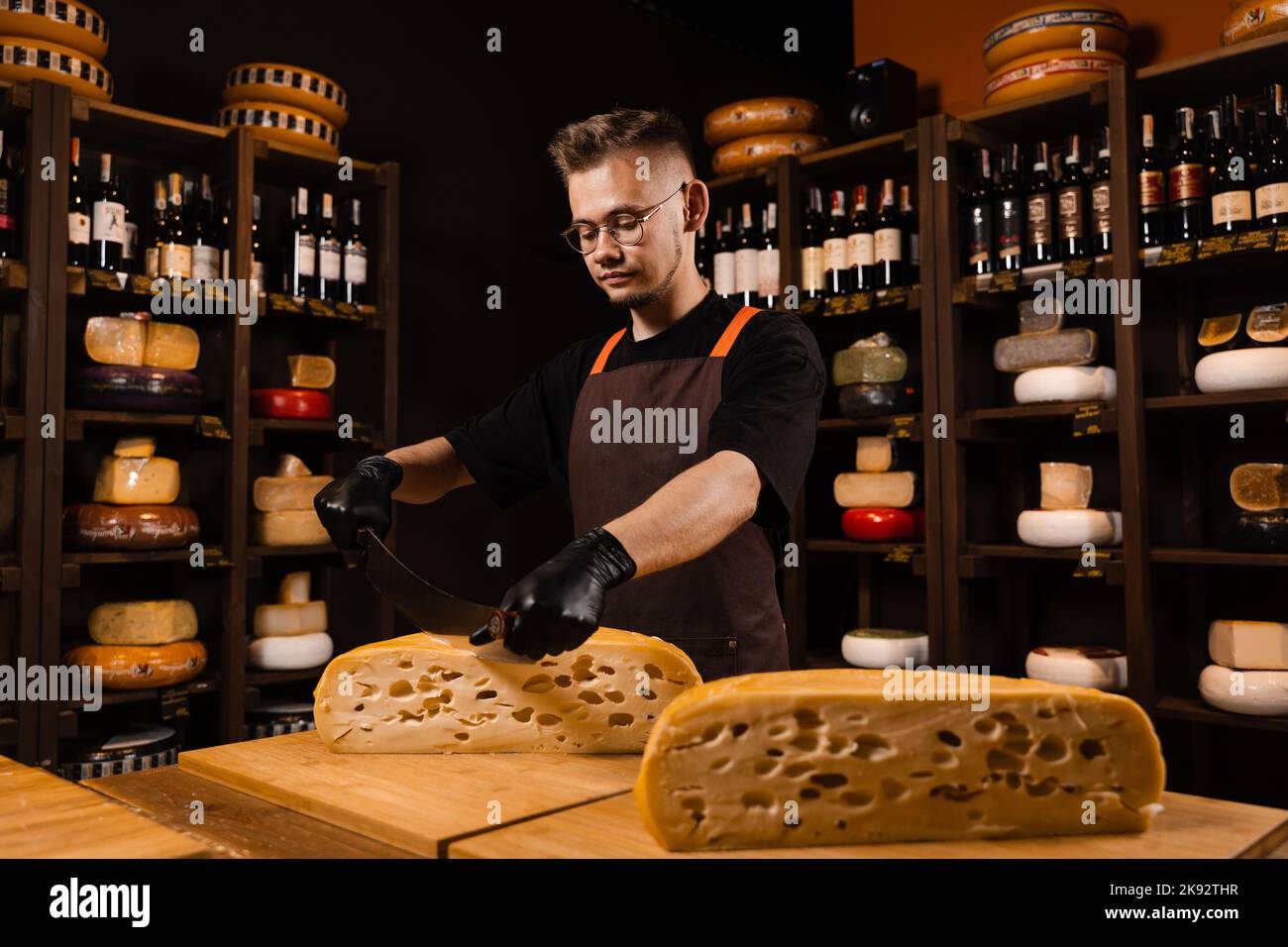 Handsome man worker of cheese shop cut limited maasdam natural aged ...