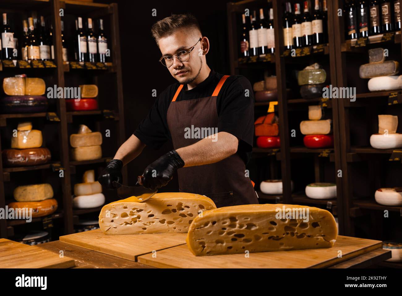 Limited maasdam cheese wheel cutting cheese in store. Cheese sommelier ...