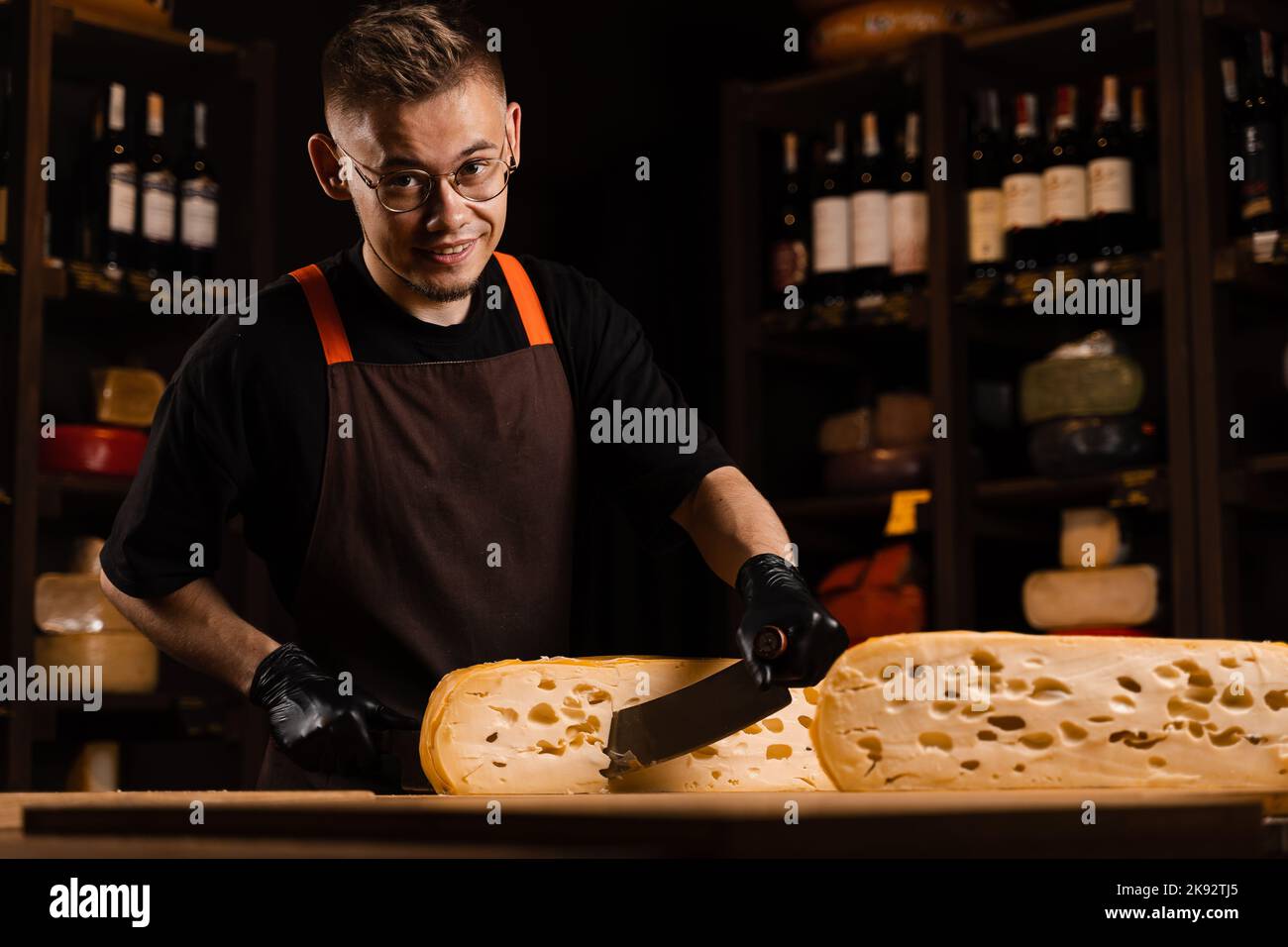 Cheese sommelier in food shop worker is cutting limited maasdam natural ...