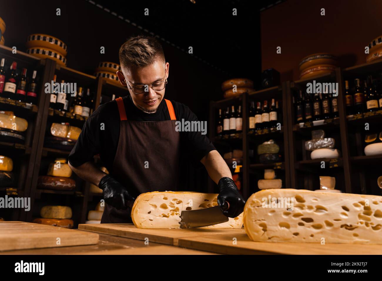 Cheese sommelier in food shop worker is cutting limited maasdam natural ...