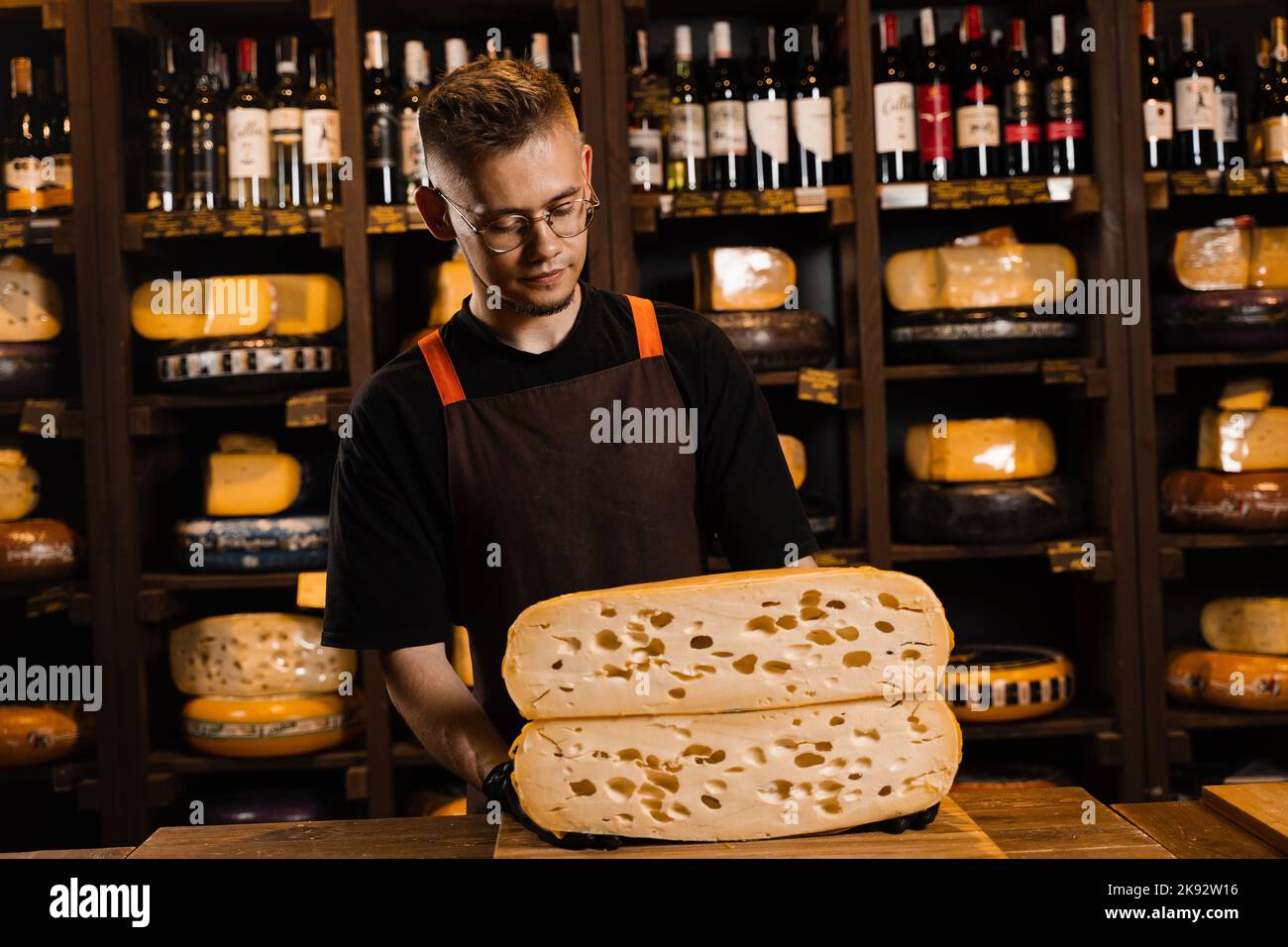Cheese sommelier in food shop worker holding 2 big pieces of cheese ...