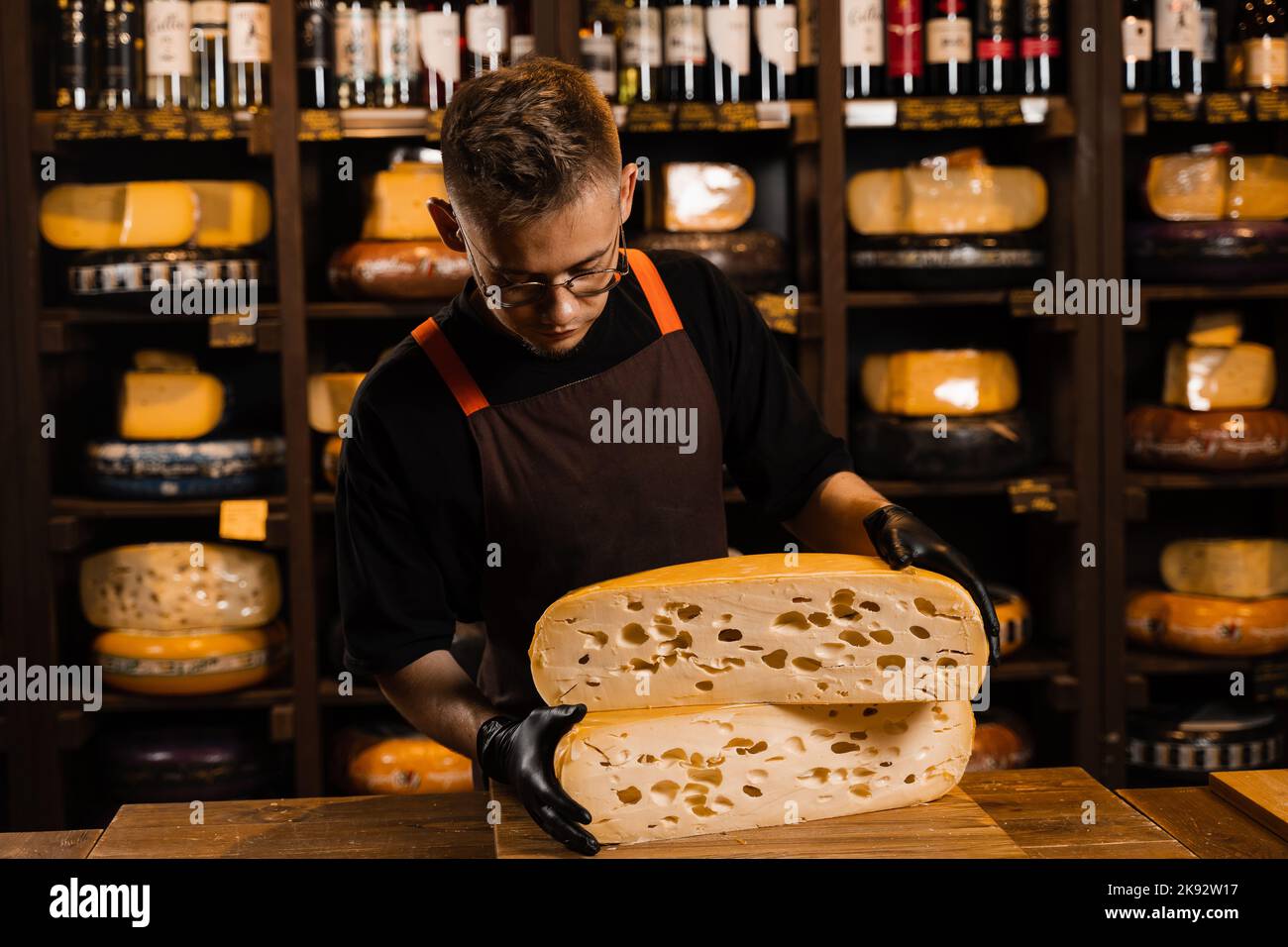 Cheese sommelier in food shop worker holding 2 big pieces of cheese ...