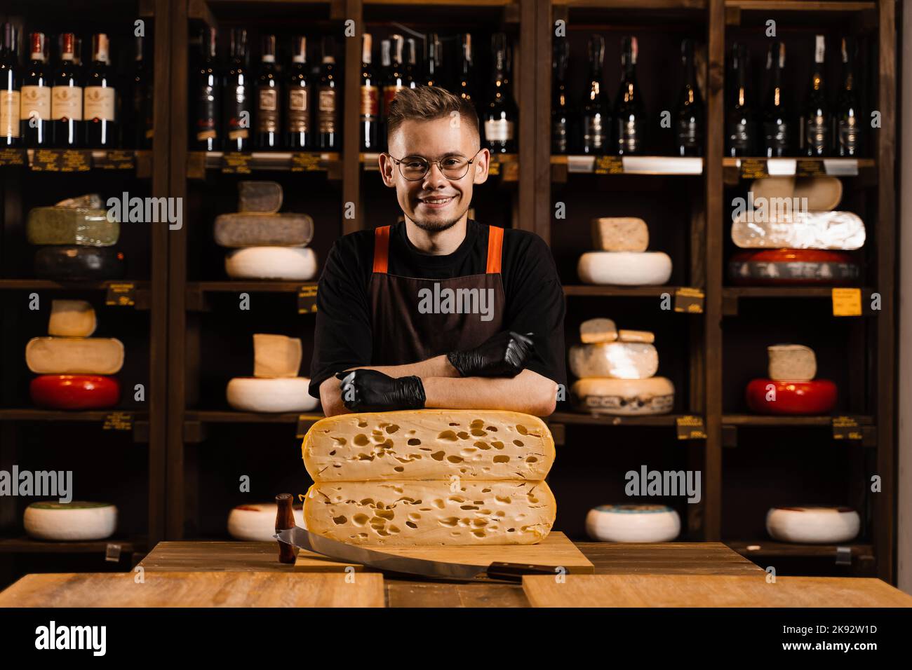 Professional cheese sommelier in food shop. Worker of cheese store with ...