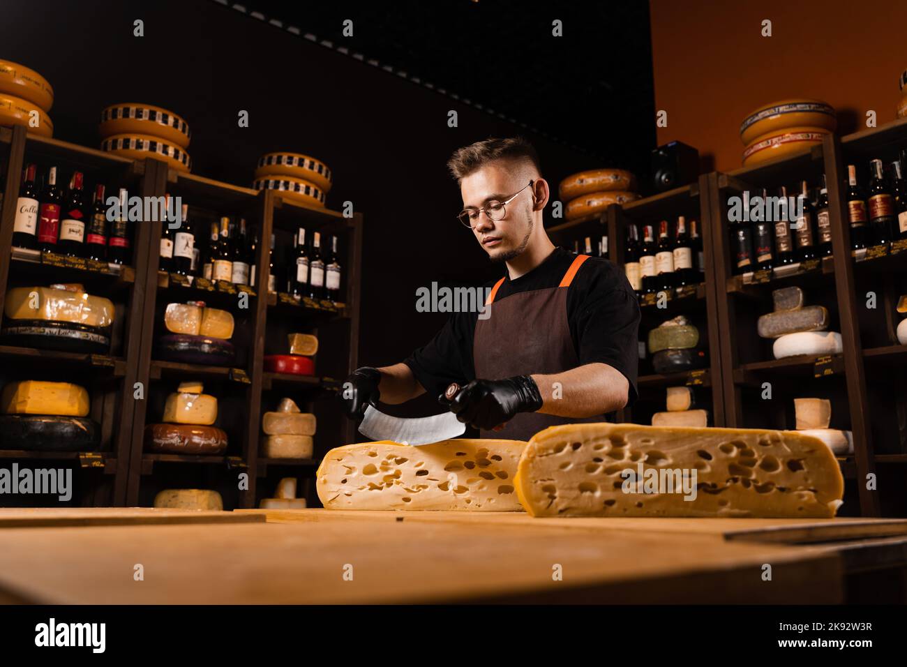 Handsome man worker of cheese shop cut limited maasdam natural aged ...