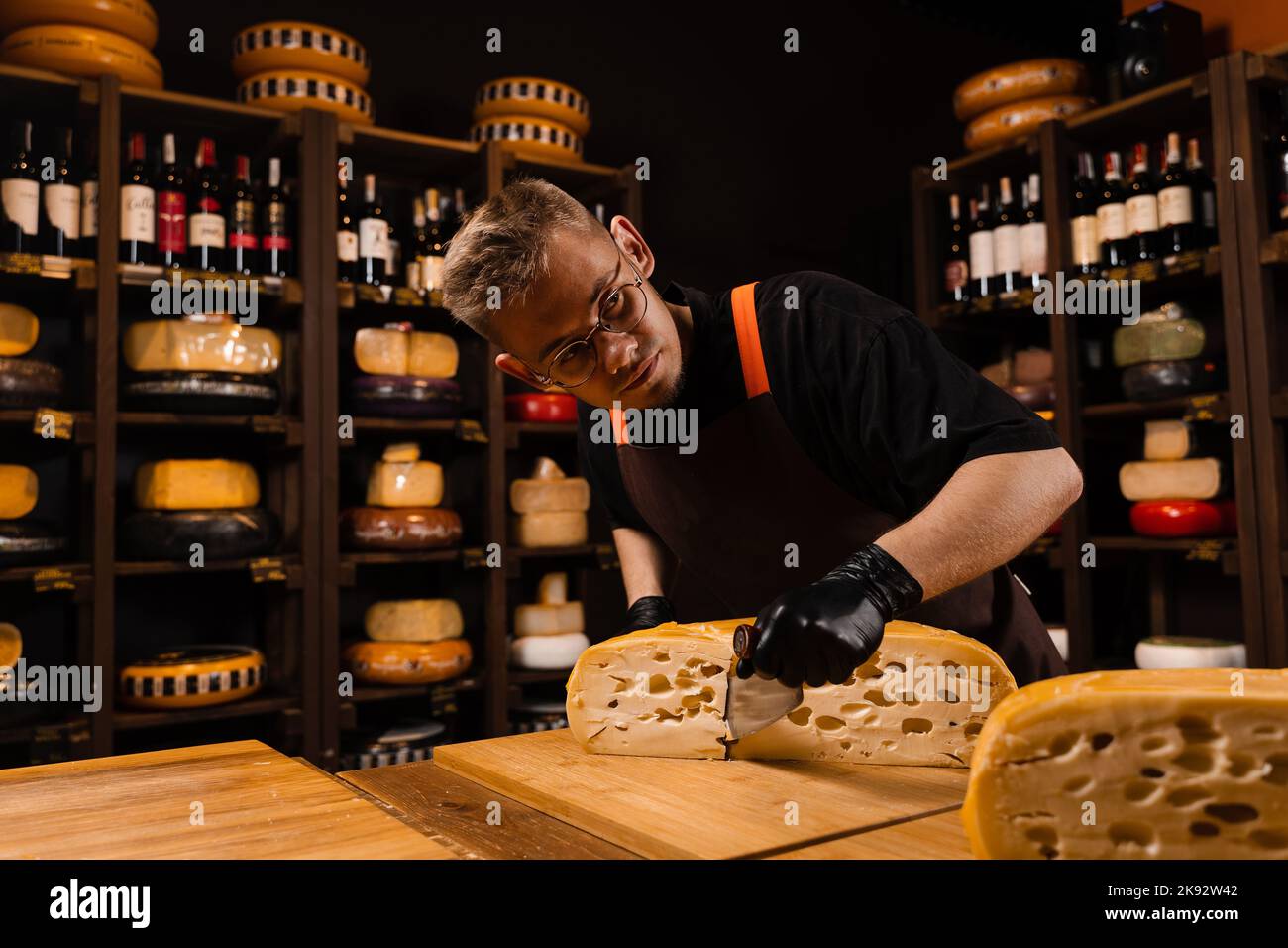 Cheese sommelier in food shop worker is cutting limited maasdam natural ...