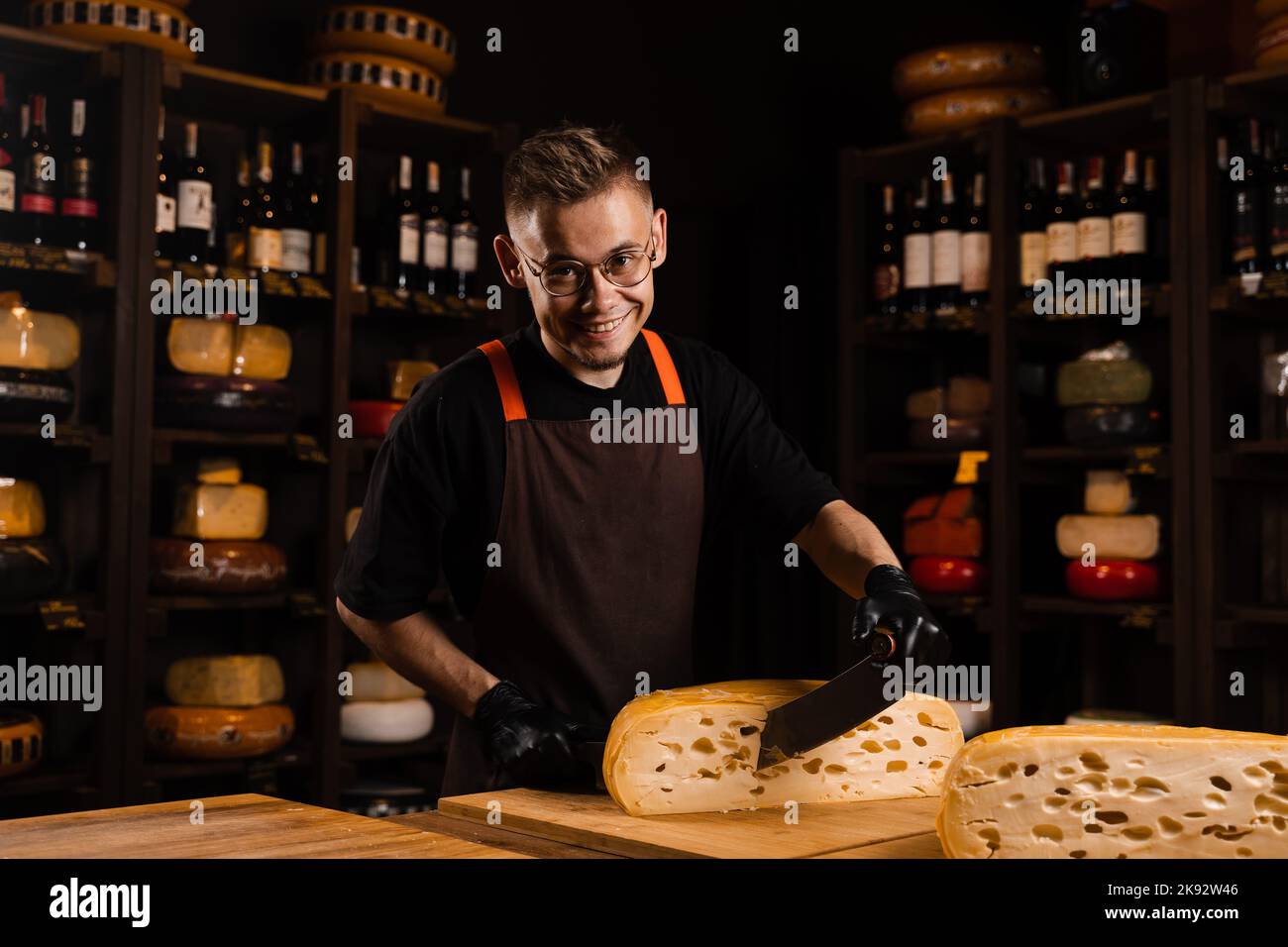 Cheese sommelier in food shop worker is cutting limited maasdam natural ...
