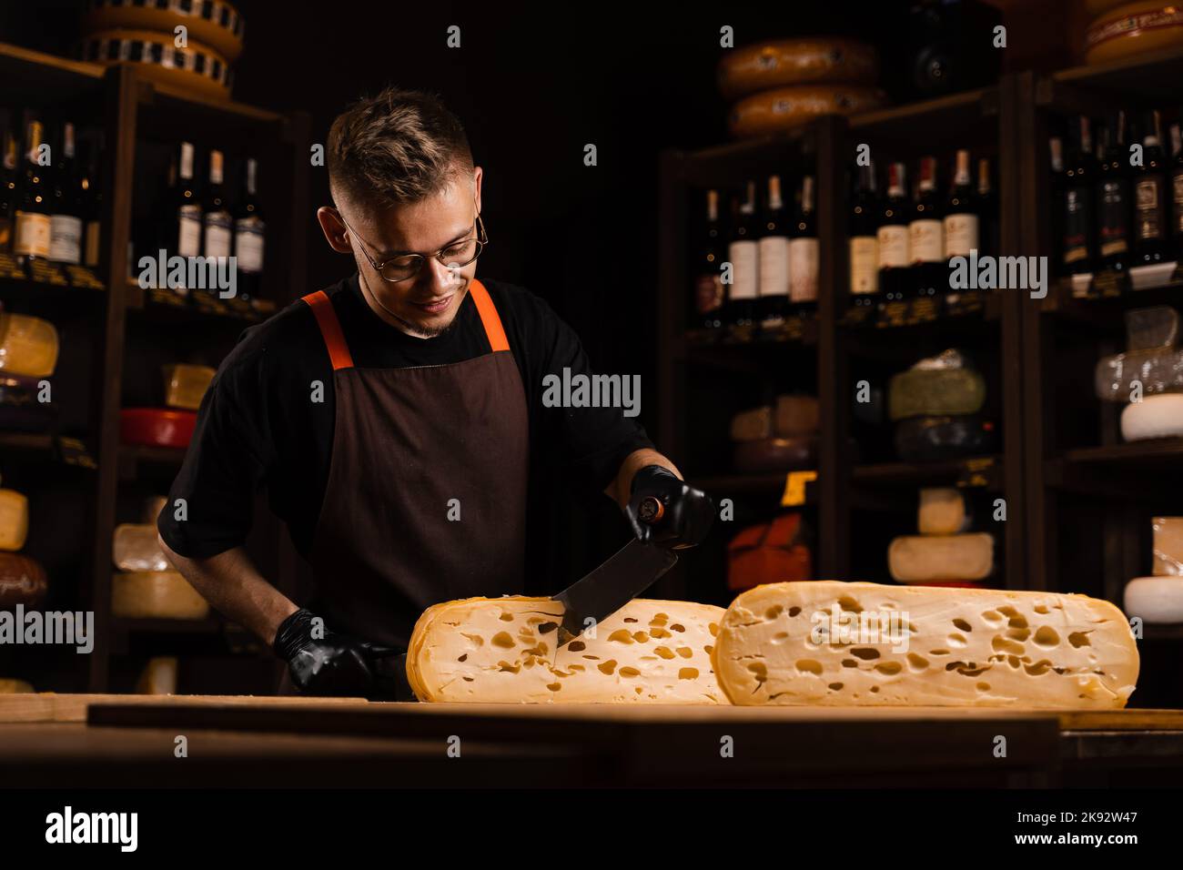 Cheese sommelier in food shop worker is cutting limited maasdam natural ...