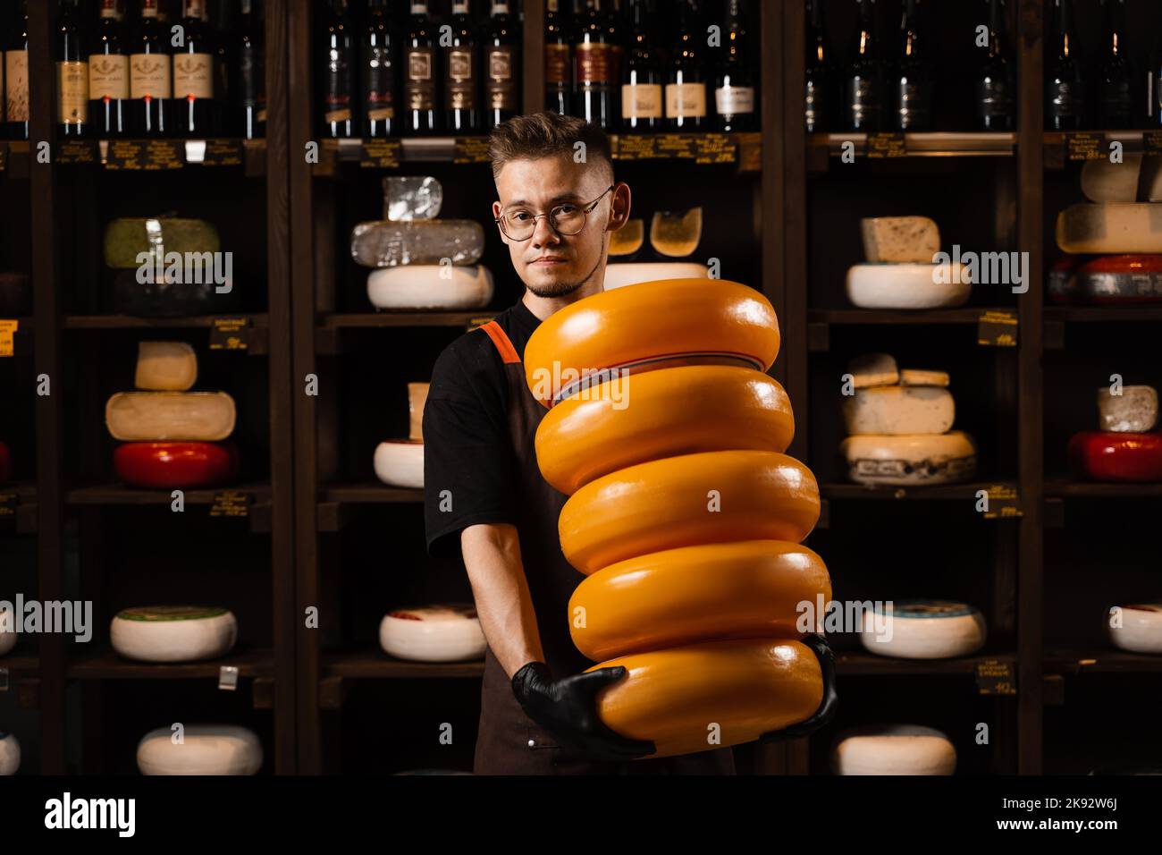 Big yellow wheels of cheese in hands of handsome sommelier. Worker of ...