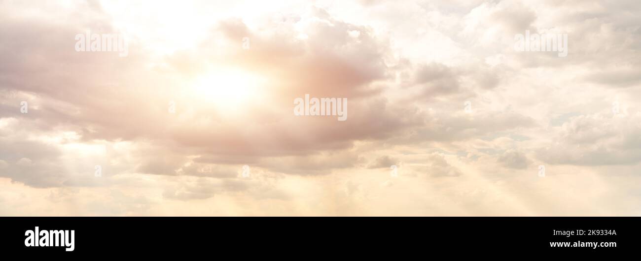 Panoramic background of a sunset cloudy sky with glimpses of the sun ...