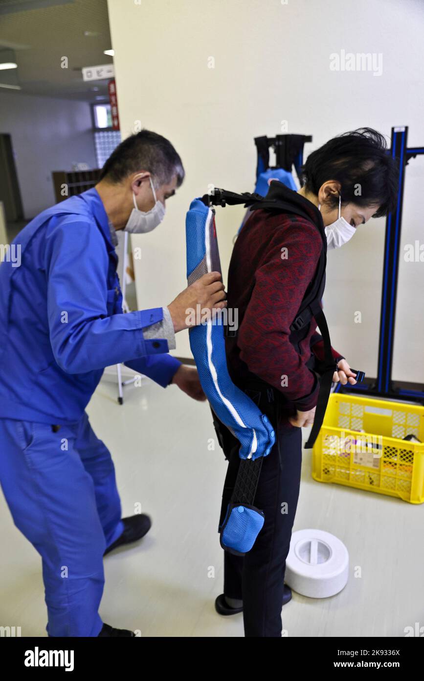 Woman being fitted with an exoskeleton to lift weights Stock Photo - Alamy