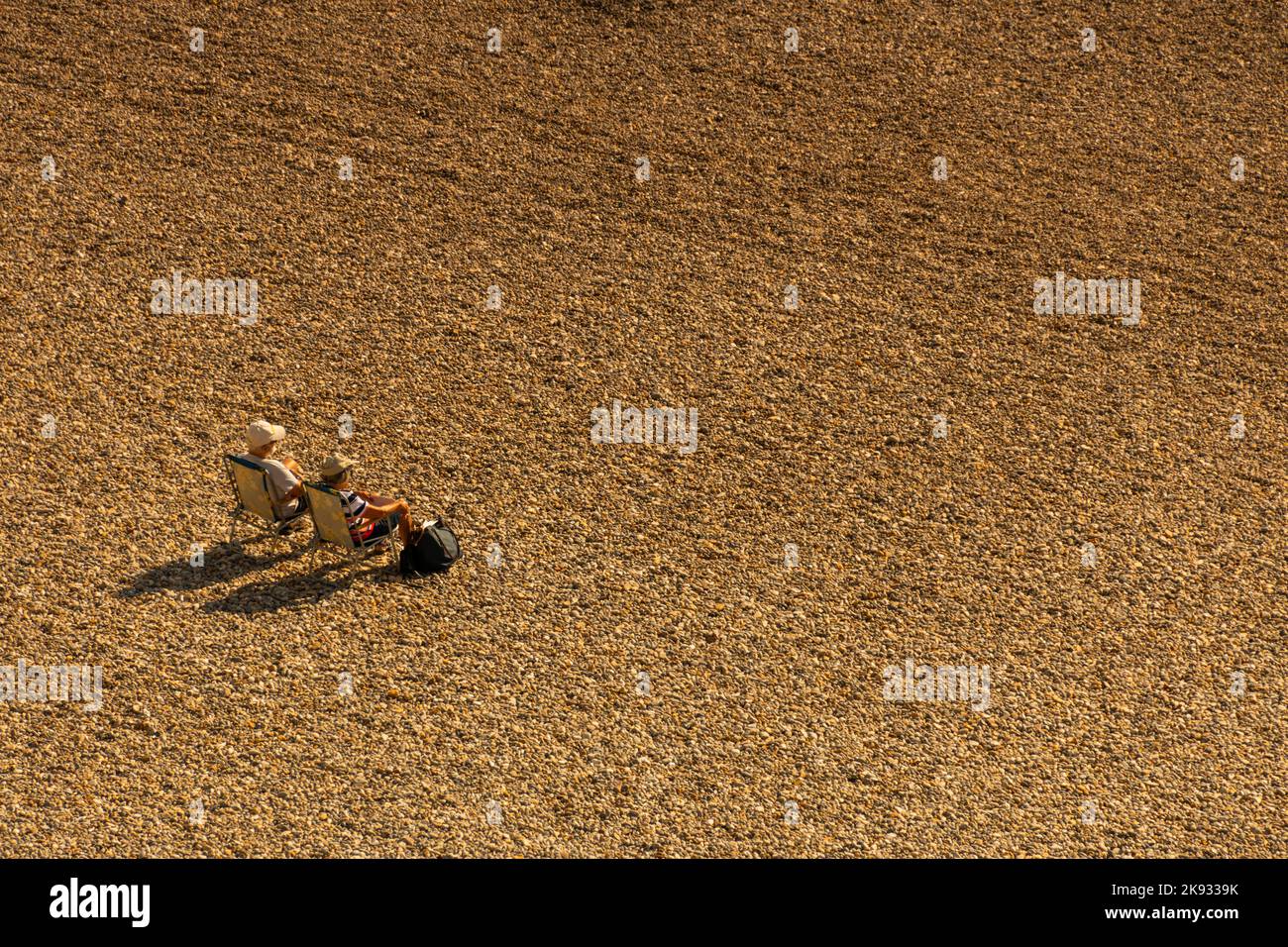 Two beachgoers relaxing on a pebble beach Stock Photo - Alamy