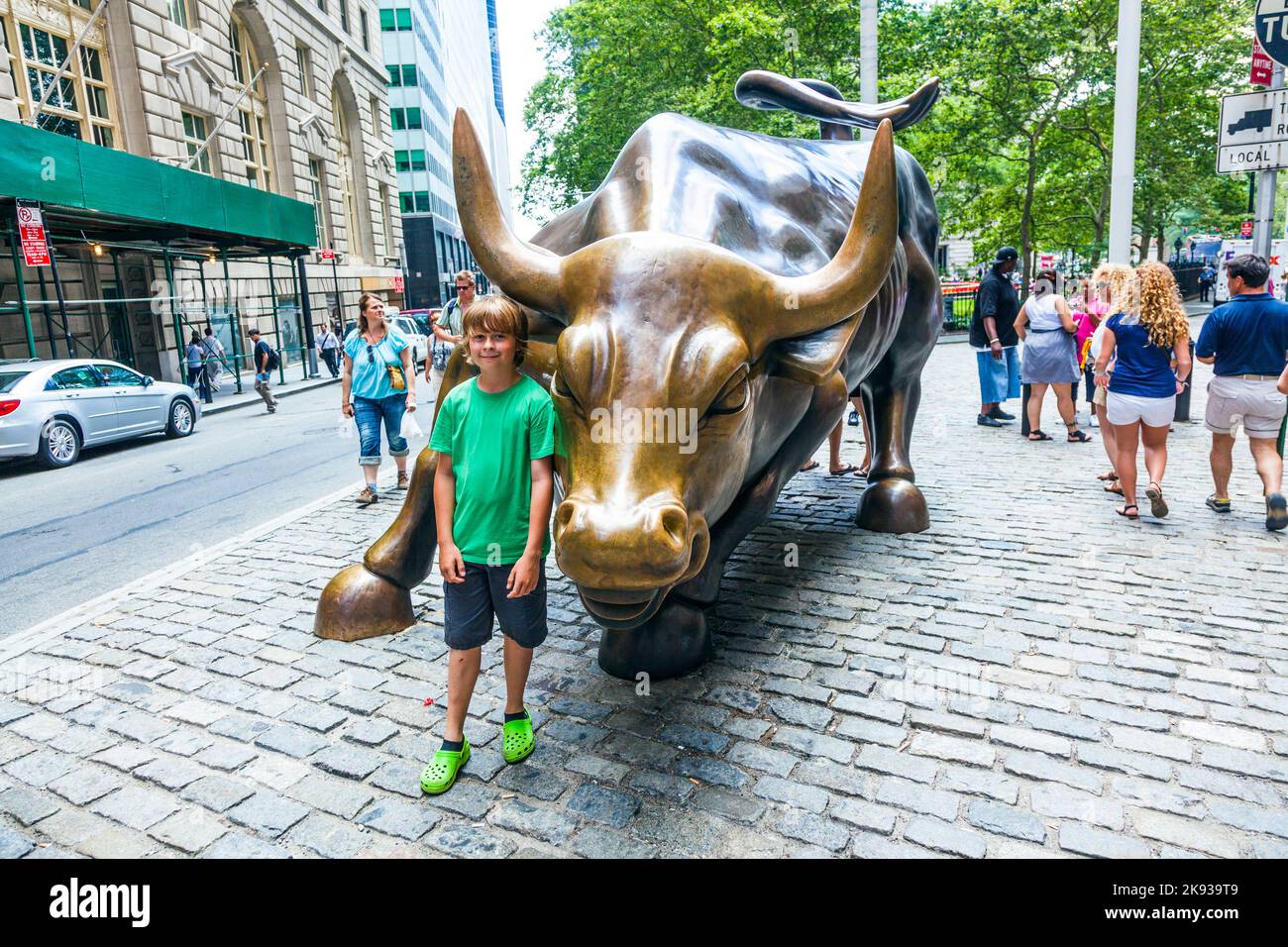 NEW YORK, USA - JULY 9, 2010: boy in front of the landmark Charging Bull in Lower Manhattan who ...