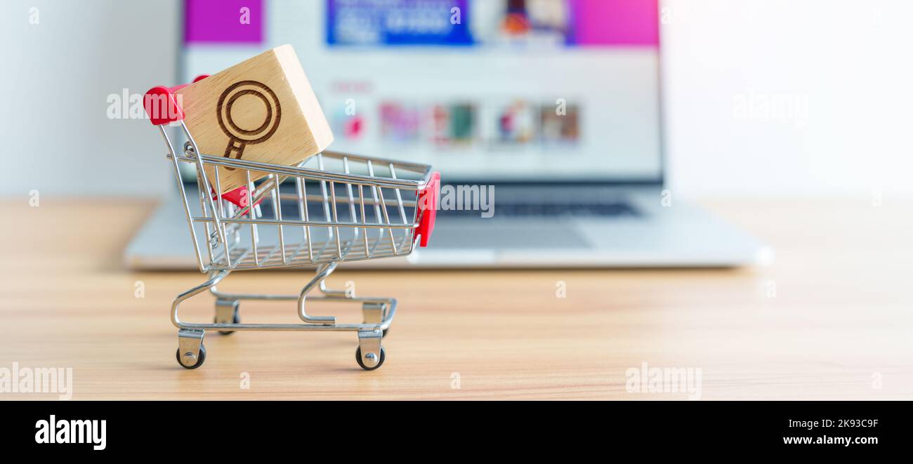 Shopping cart with Magnifying icon block and laptop computer with ...