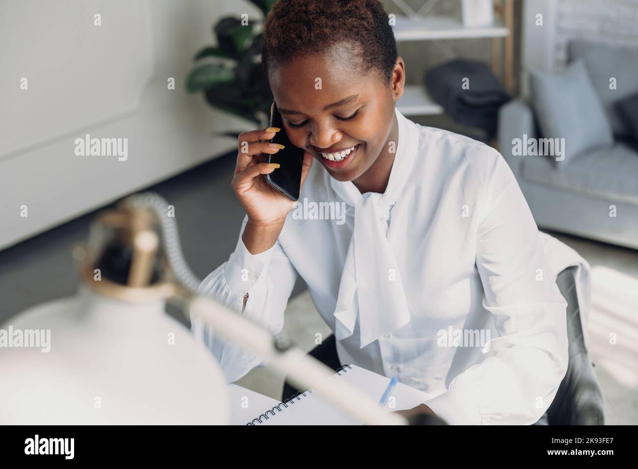 Pretty african american woman having phone conversation at office desk ...