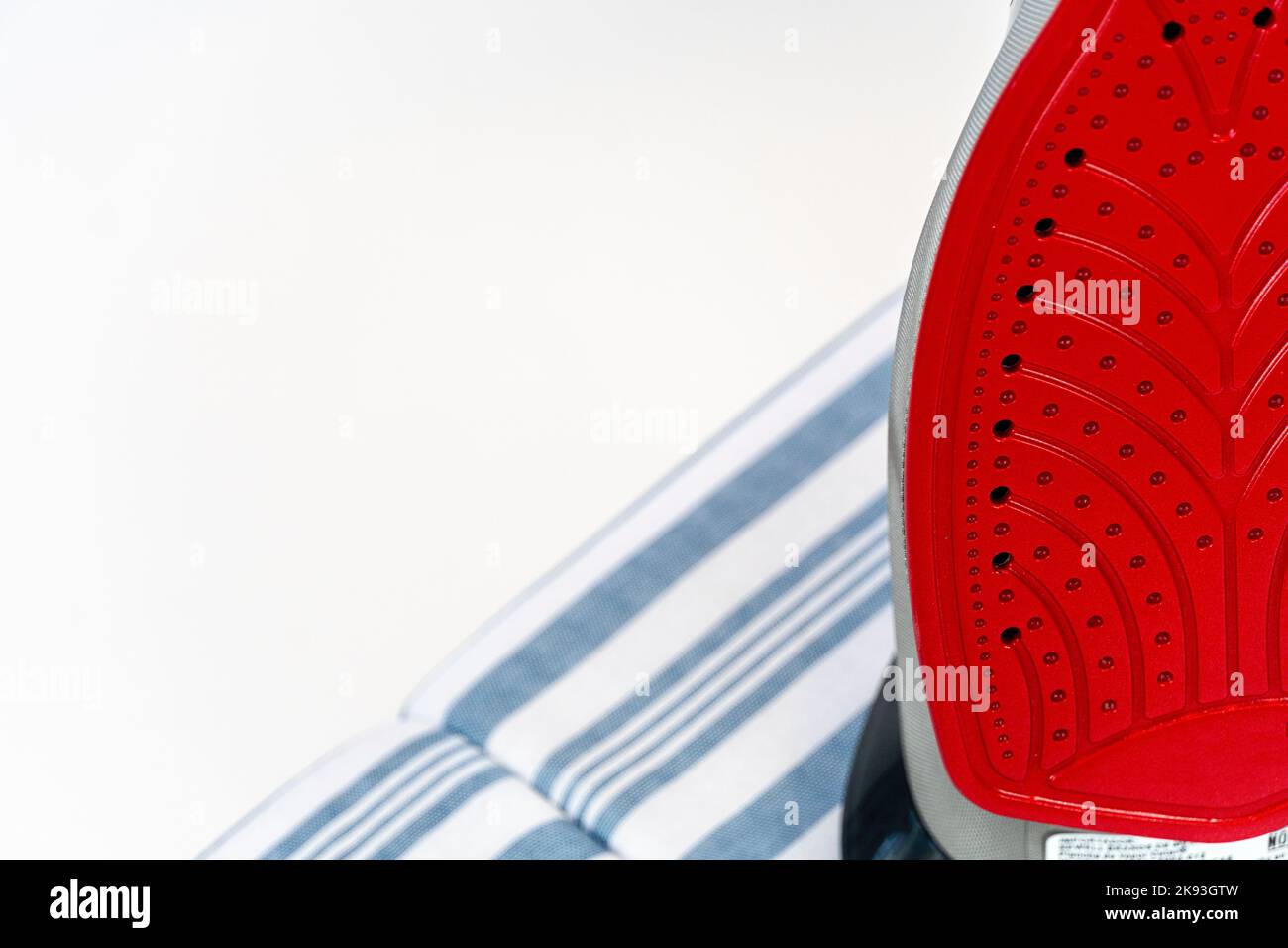 new clothes iron on white background, red ceramic iron, and blue fabric ...