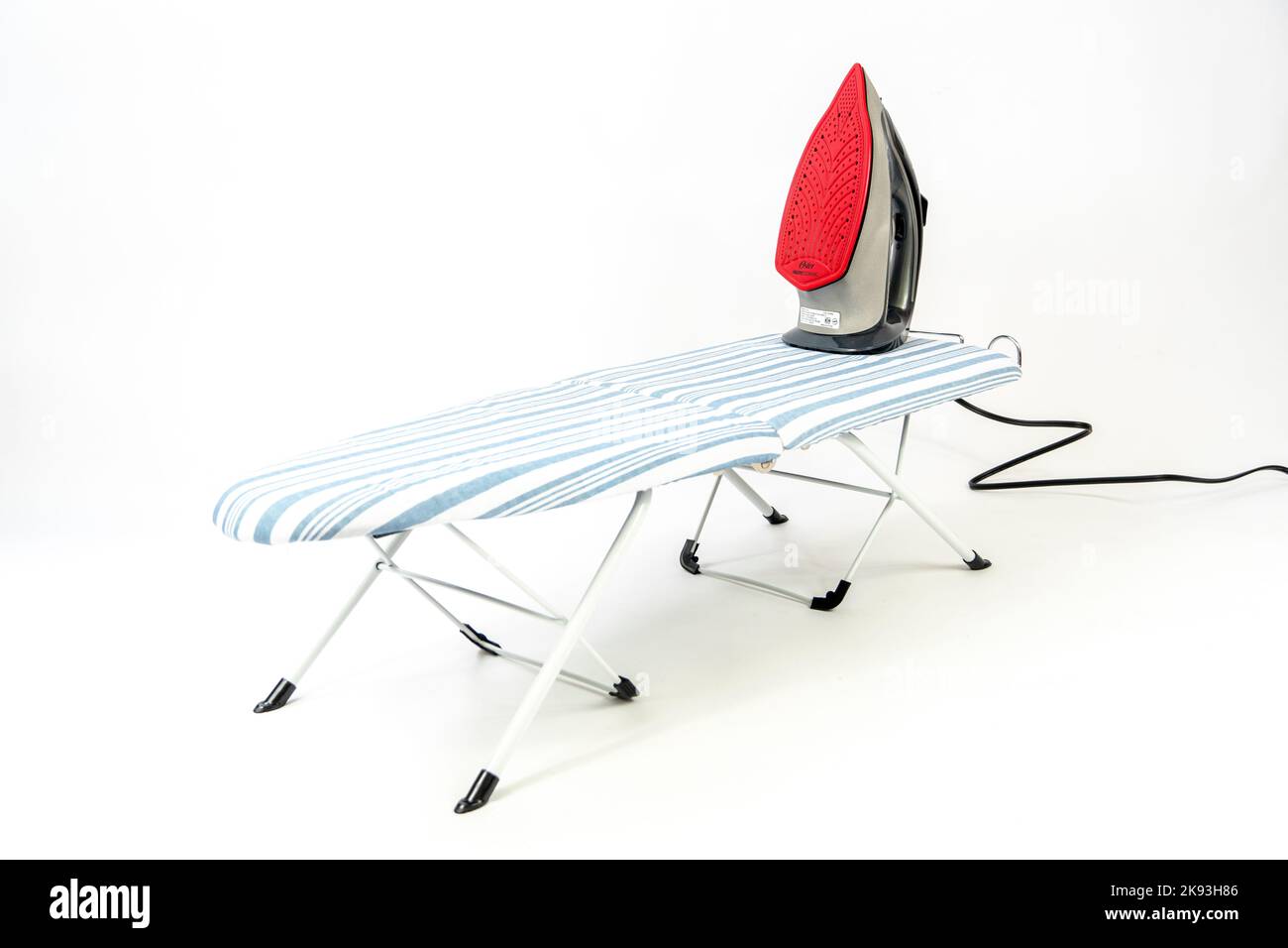 new clothes iron on white background, red ceramic iron, and blue fabric ...