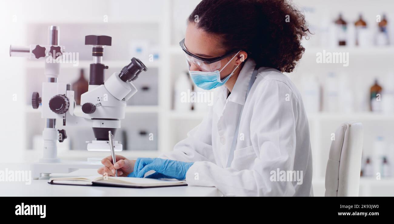 Delving into new scientific research. a young scientist writing notes ...