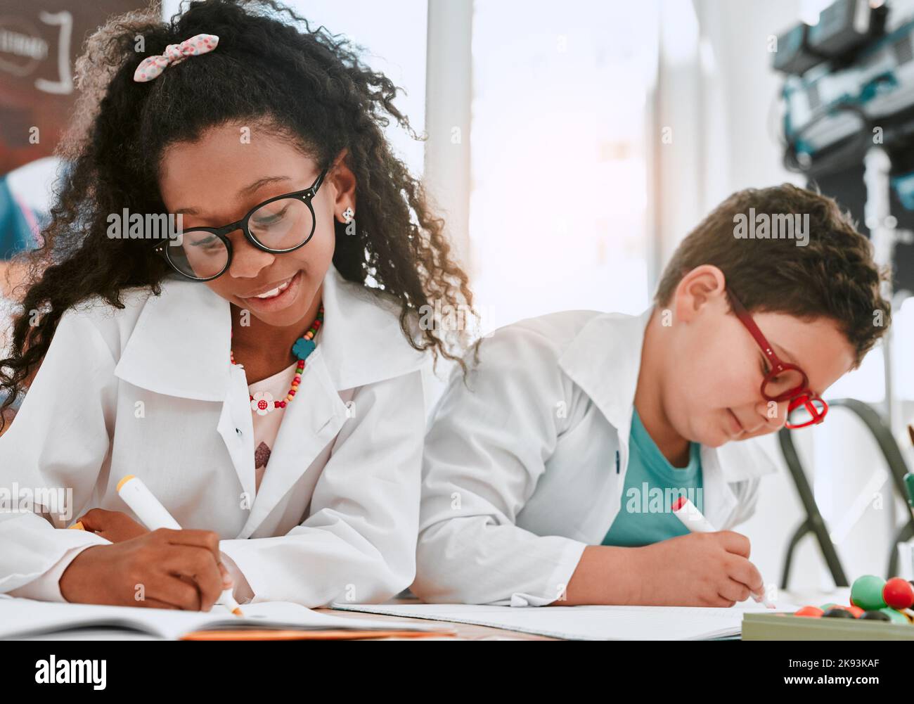 Young minds at work. two adorable young school pupils writing notes in ...