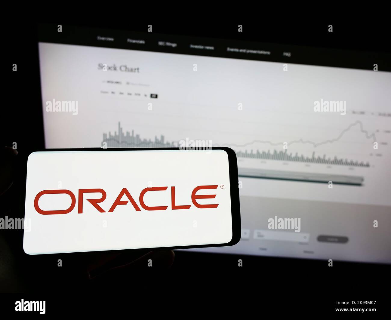 Person holding mobile phone with logo of American technology company Oracle Corporation on ...