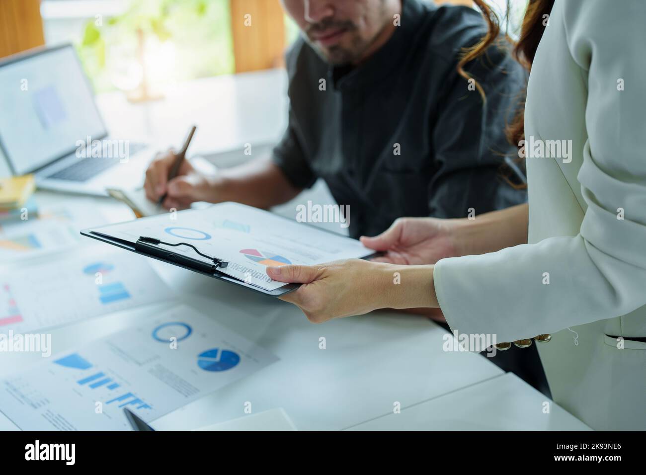 A portrait of a female marketer and a male salesperson discussing how to increase sales by ...